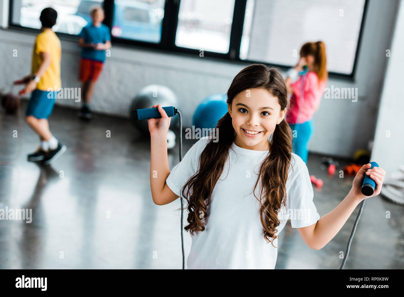 Excited brunette kid posing with skipping rope Stock Photo - Alamy