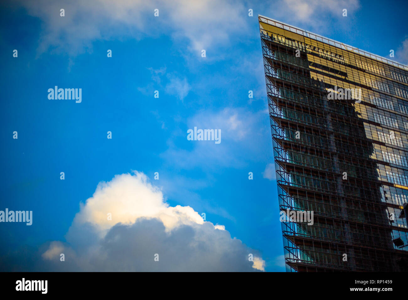 A blue sky and clouds background an artistic view of the Atrium Tower ...