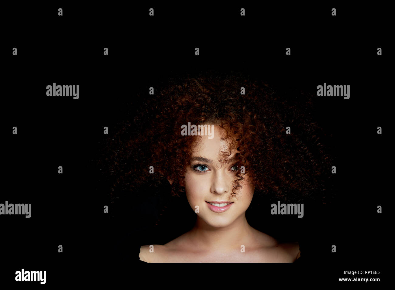 A Girl With Lush Curly Red Hair Open Shoulders Corrects Hair And