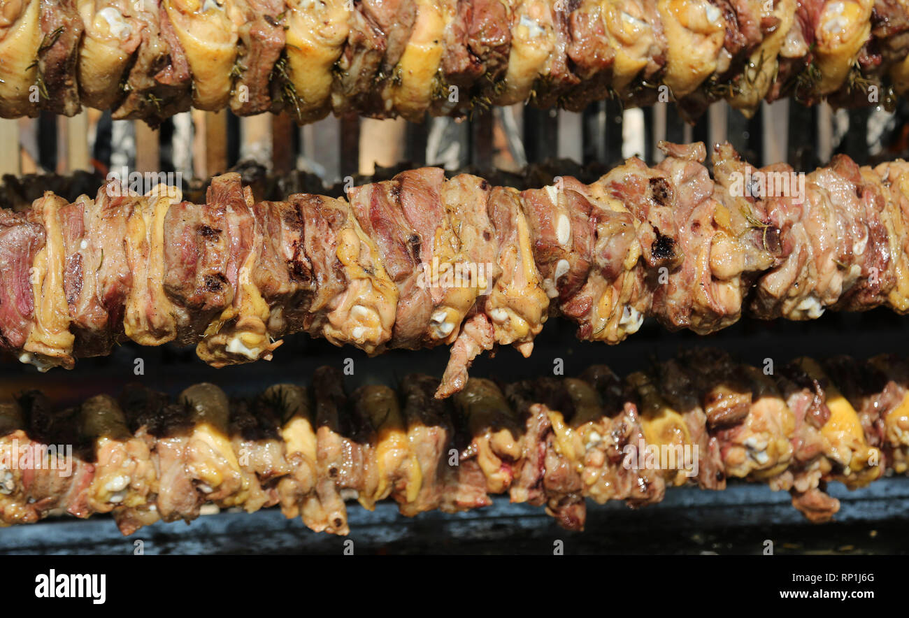 large spit with chicken meat and pork cooked slowly in the rotisserie ...