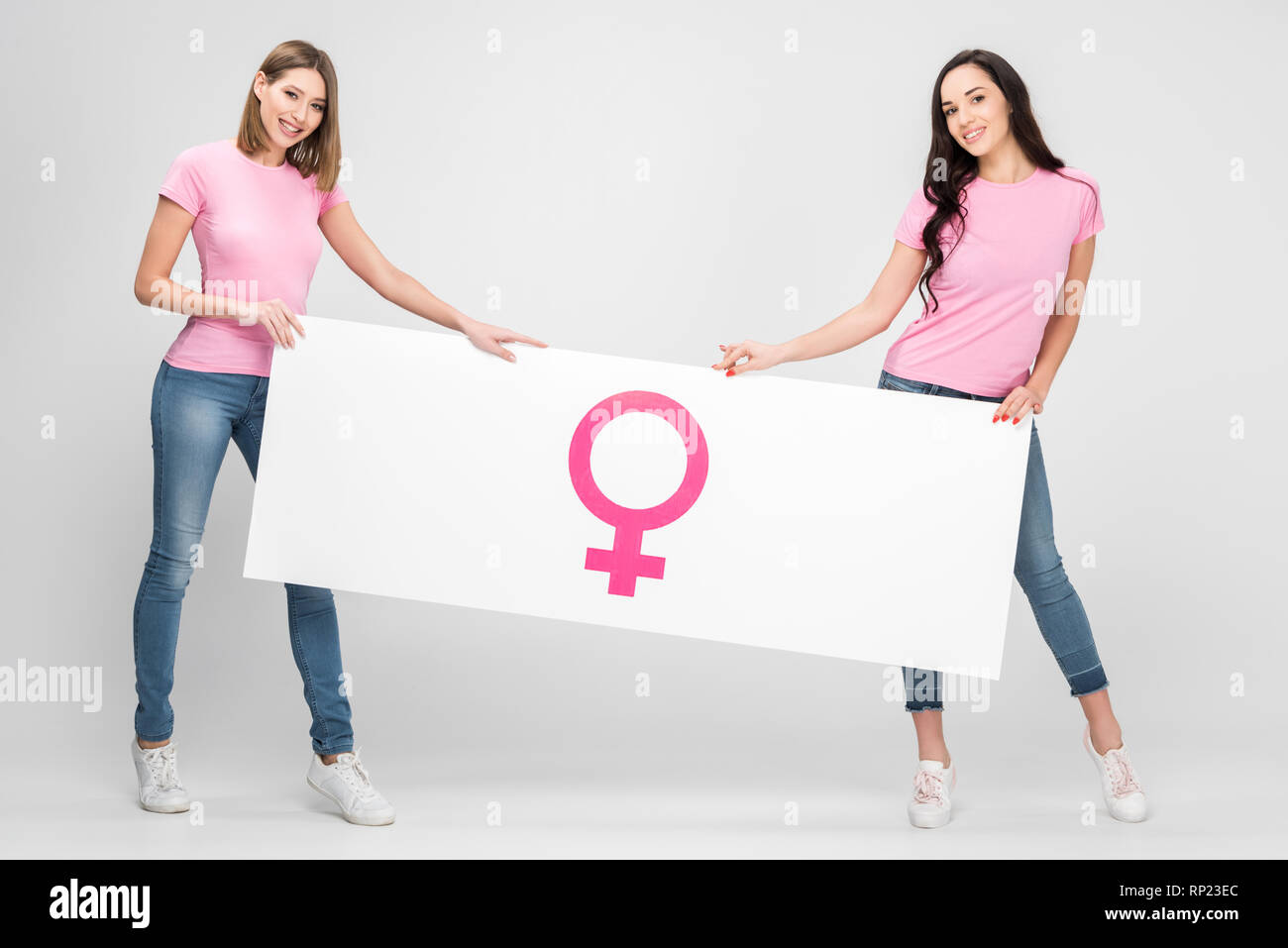 cheerful women holding large sign with female symbol on grey background ...
