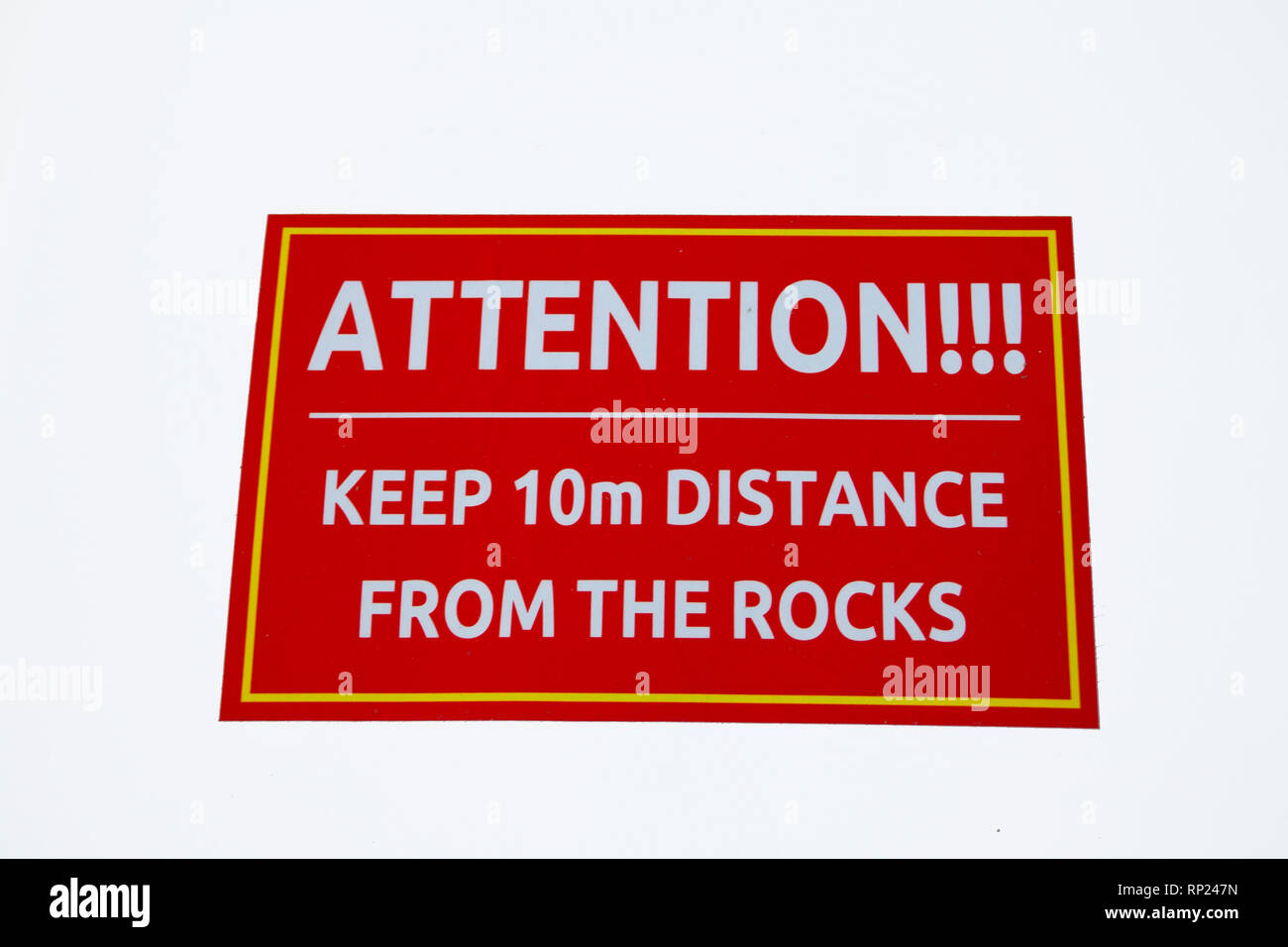 Red board with warning sign to stay away from the rocks. Danger warning ...