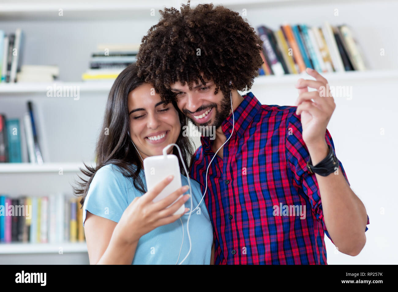 Hipster couple streaming song with phone and listening music indoors at ...