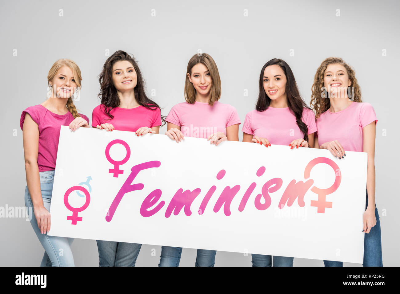 cheerful girls holding large sign with feminism lettering isolated on ...