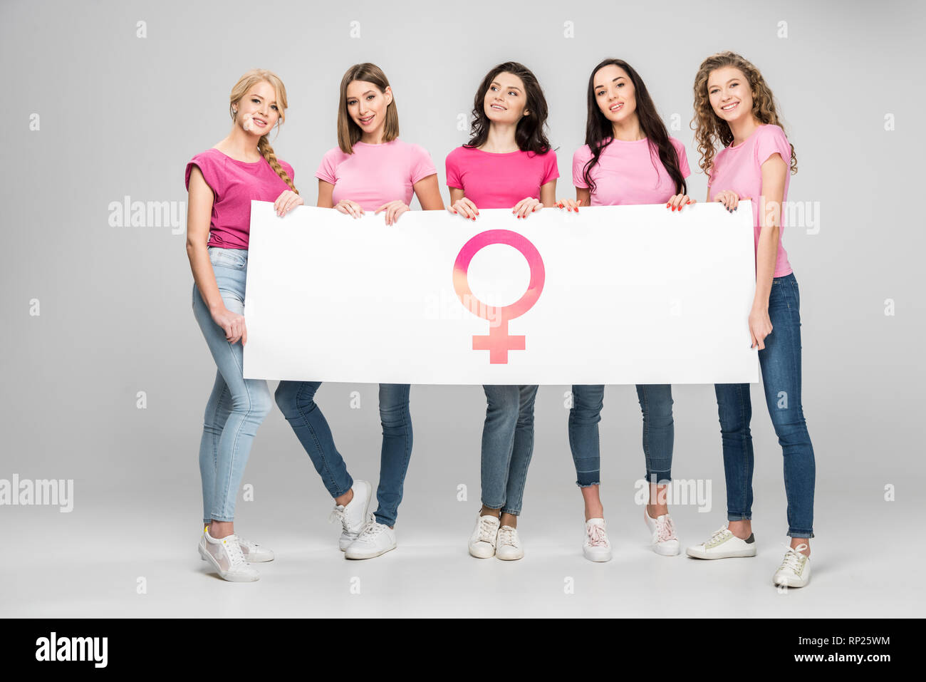 attractive young women holding large sign with female symbol on grey ...