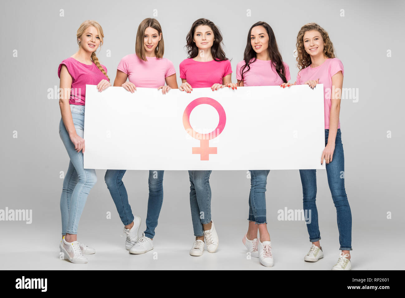 attractive girls holding large sign with female symbol on grey ...