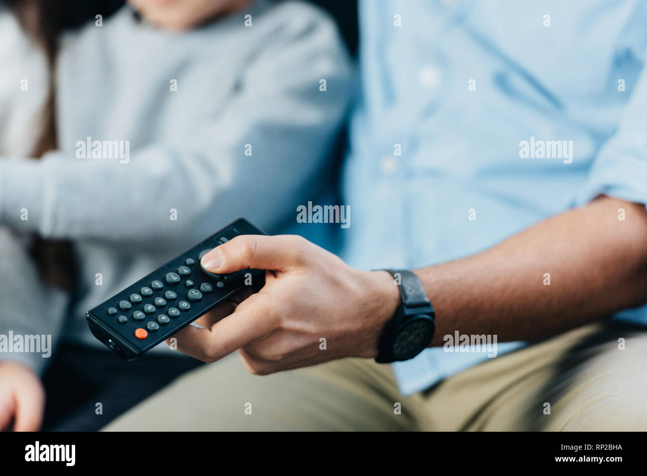 cropped view of man holding remote control in hand near kids Stock ...