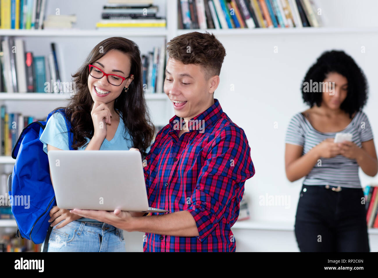 Laughing male student with nerdy girl at computer at classroom of ...