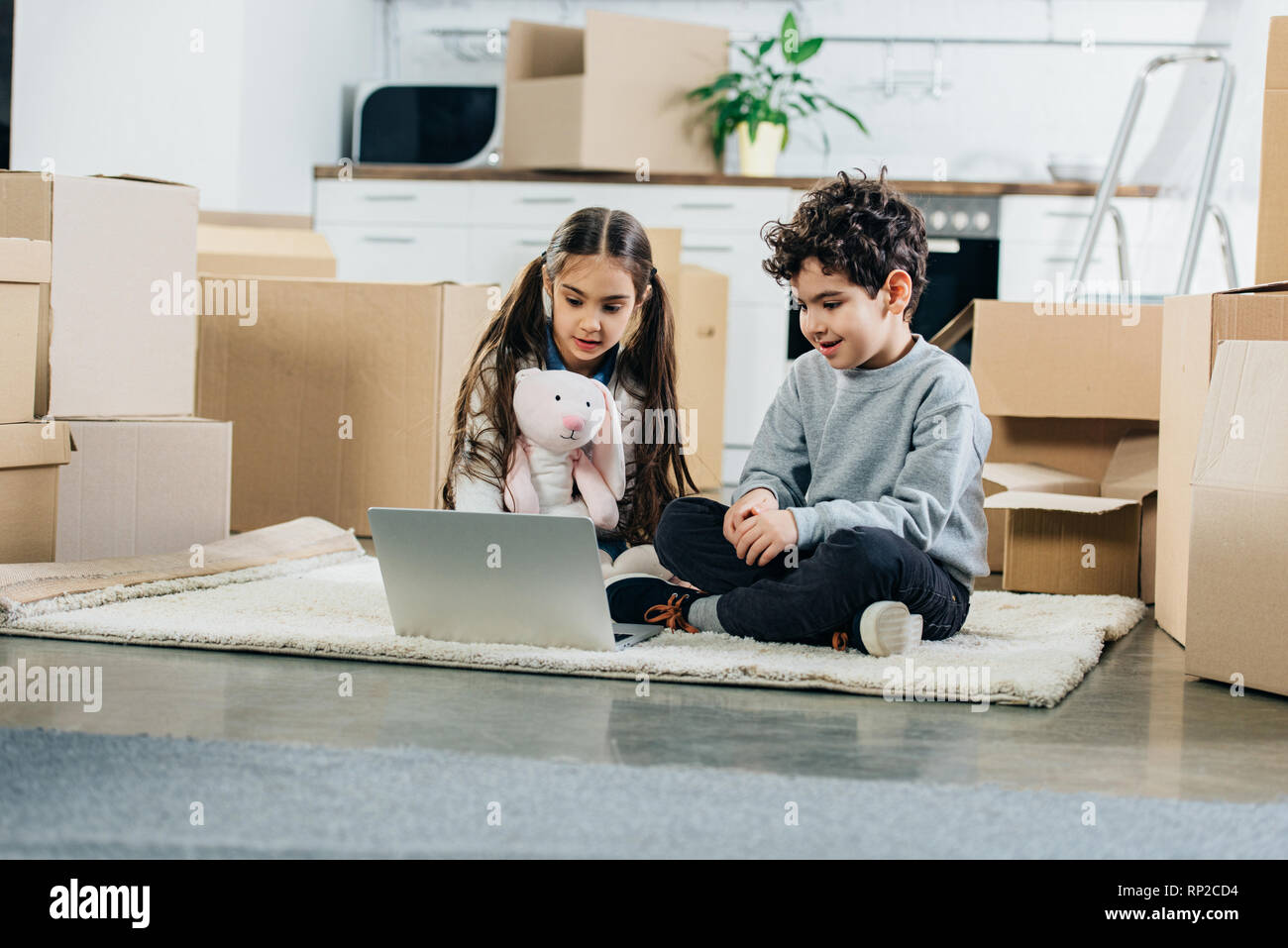 happy children using laptop while sitting on carpet in new home Stock ...