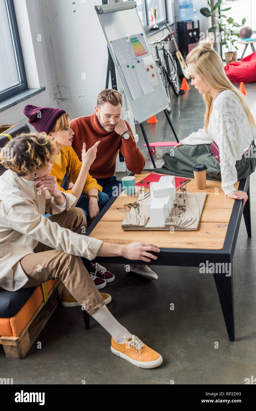 concentrated group of female and male architects sitting at table and ...