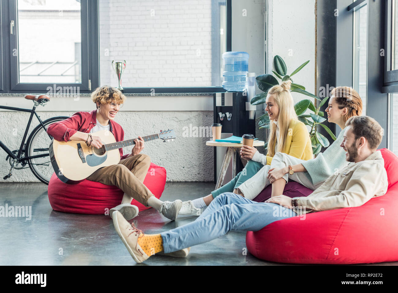 group of friends sitting on bean bag chairs with coffee to go and ...