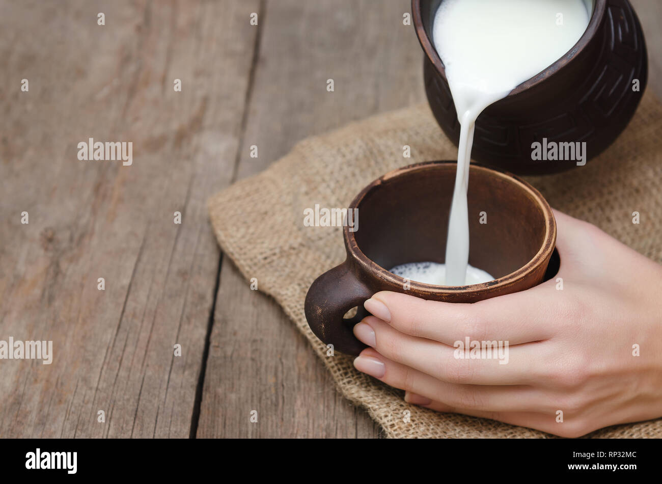Fresh milk pouring in a clay cup on wooden background Stock Photo - Alamy