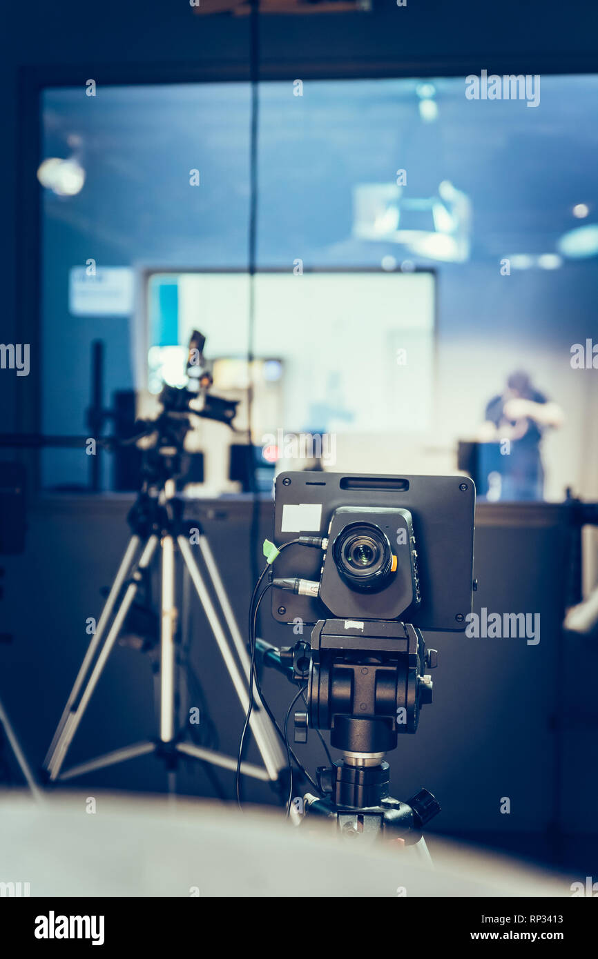 Film camera on a tripod in a television broadcasting studio, spotlights ...