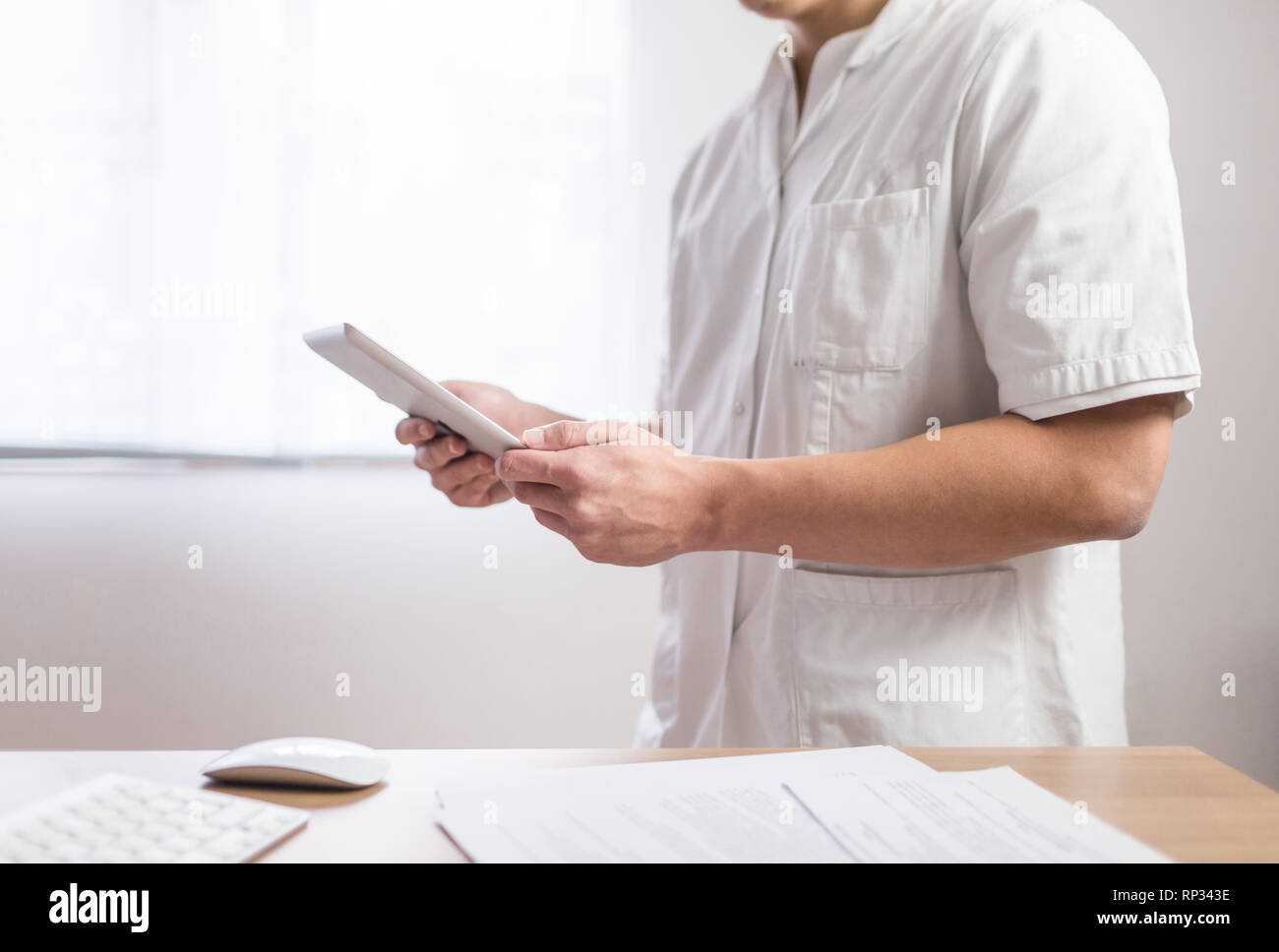Doctor in the uniform using computer tablet next to his office desk in ...
