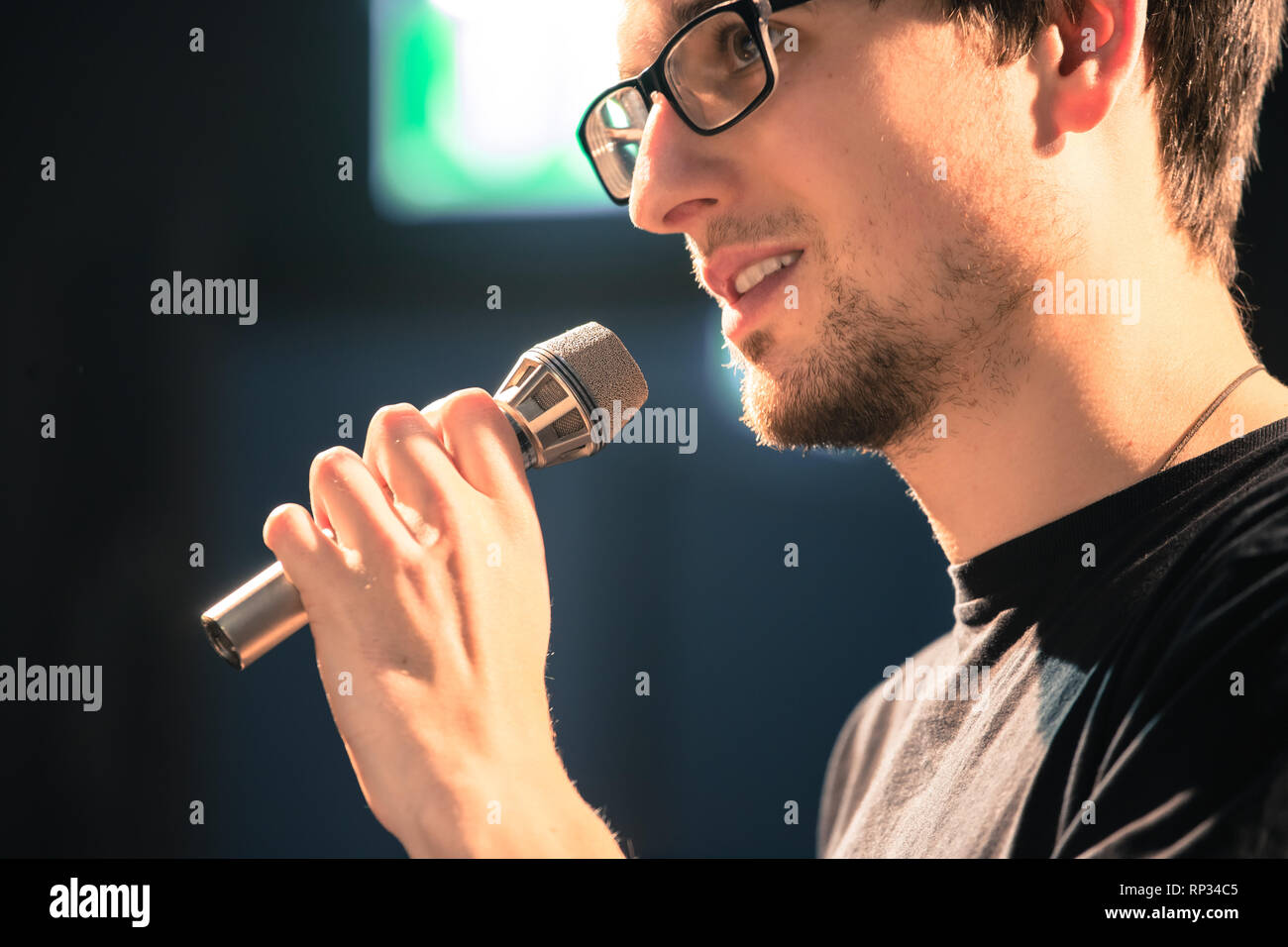 Young man on the stage is talking into a microphone, speech Stock Photo ...
