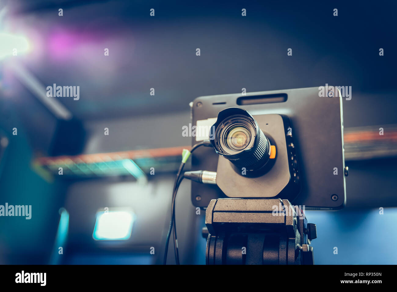 Film camera on a tripod in a television broadcasting studio, spotlights ...