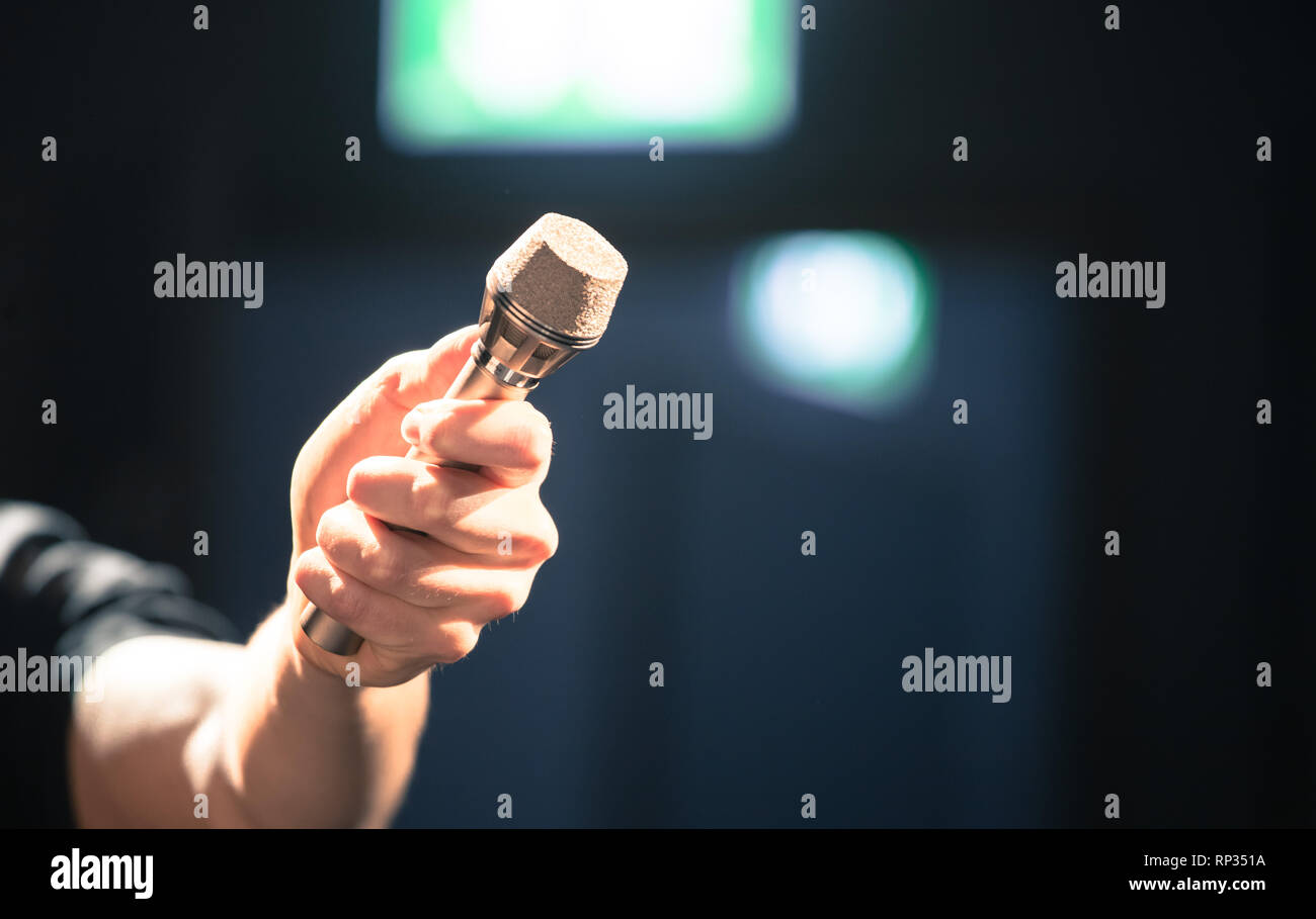 Person is holding up a metal microphone and wants to interview someone ...