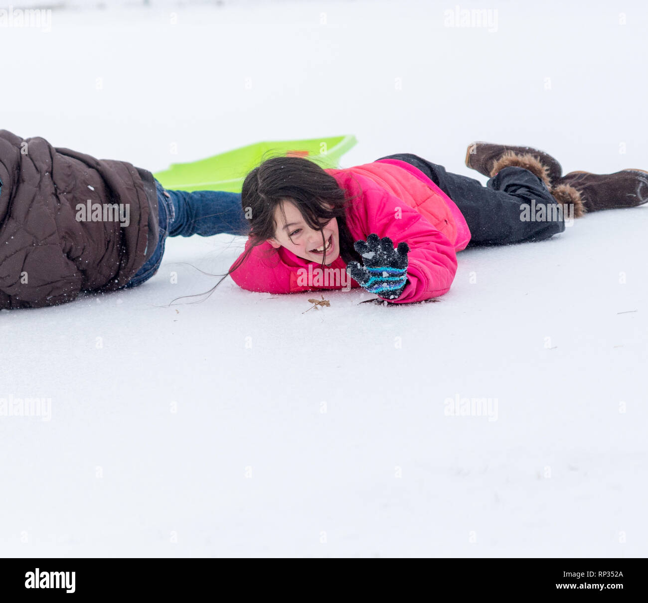 Young Asian girl laying snow next to sled Stock Photo - Alamy