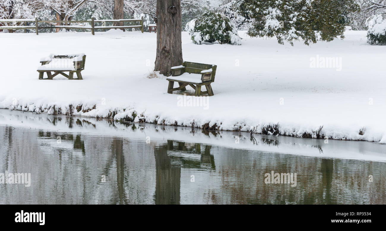 two benches covered with snow next to pond Stock Photo - Alamy