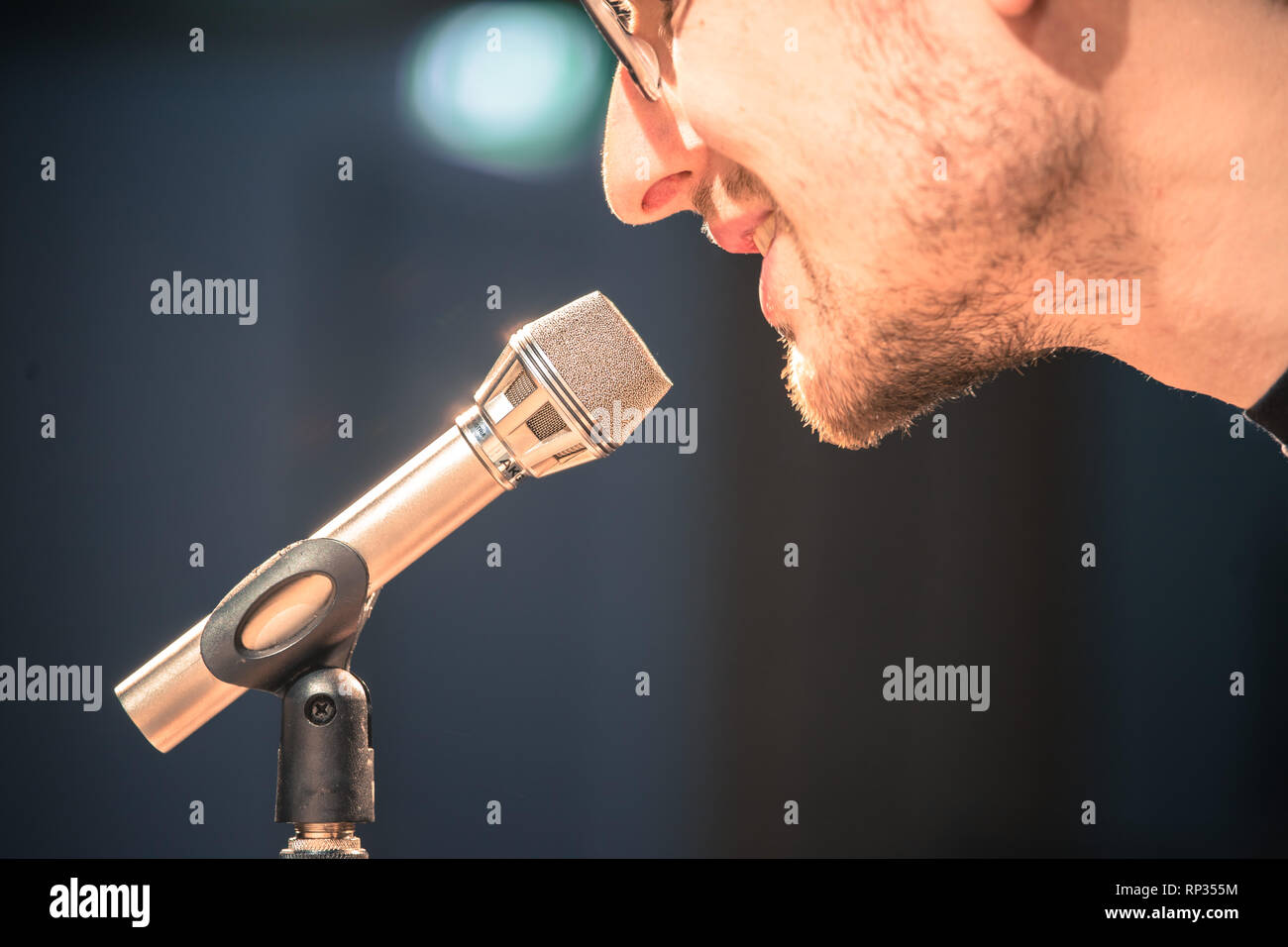 Young man on the stage is talking into a microphone, speech Stock Photo ...