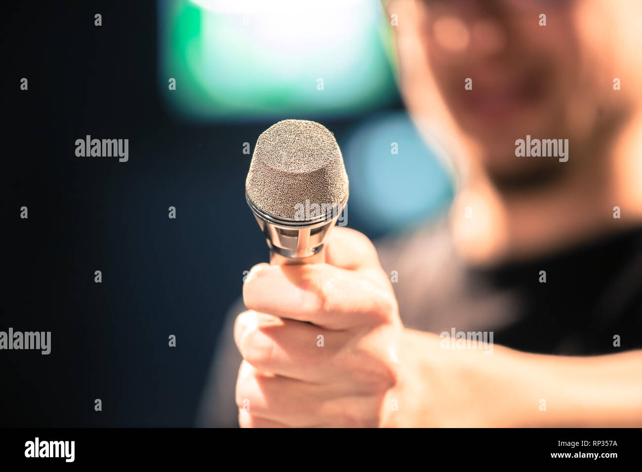 Young man on the stage is talking into a microphone, speech, face is ...