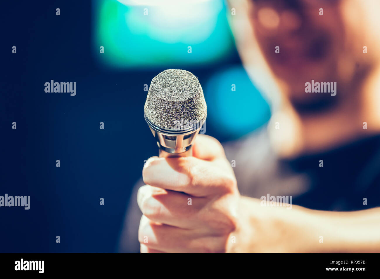 Young man on the stage is talking into a microphone, speech, face is ...