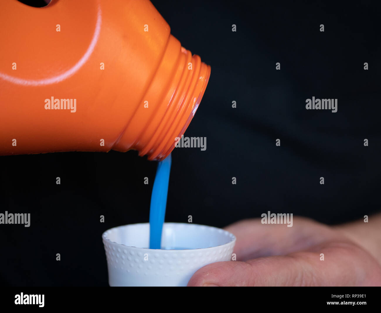 close-up of small portion cap of liquid detergent and blue gel fluid ...