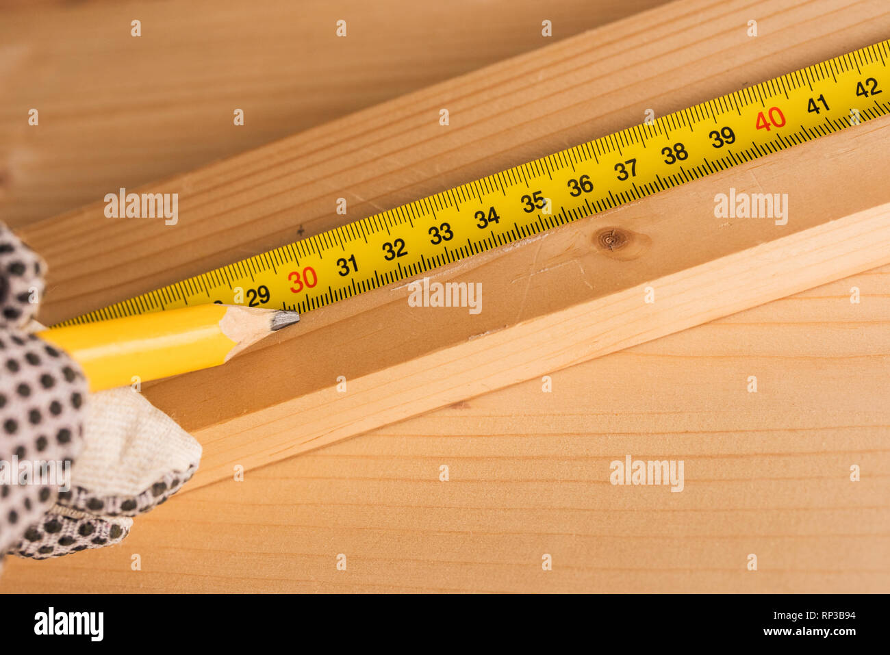 Carpenter marking pine wood plank for cutting in woodwork workshop ...