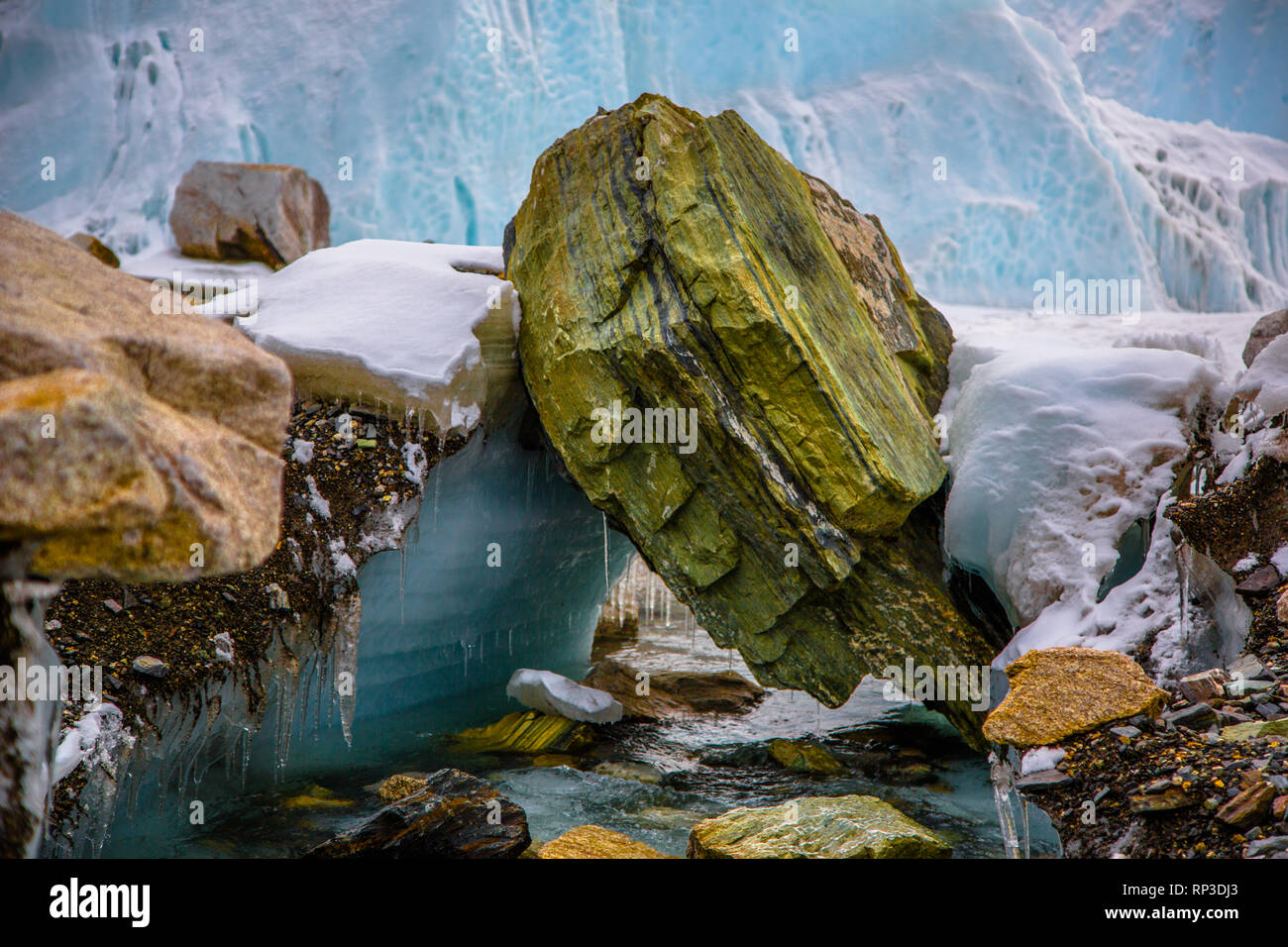 A large boulder balancing precariously between two melting ice blocks ...