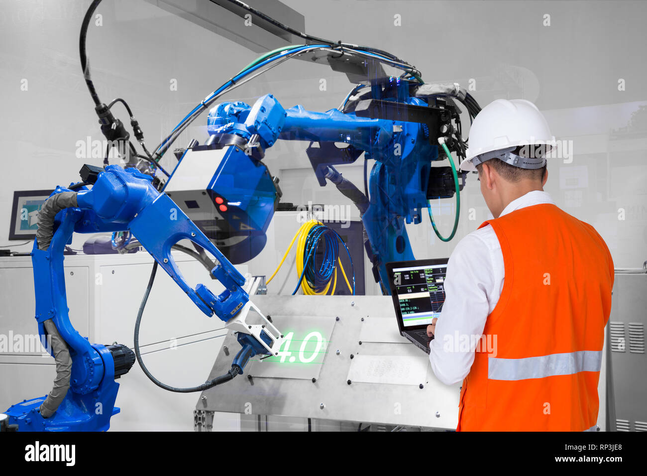 Engineer using laptop computer control laser robotic cutting on metal ...