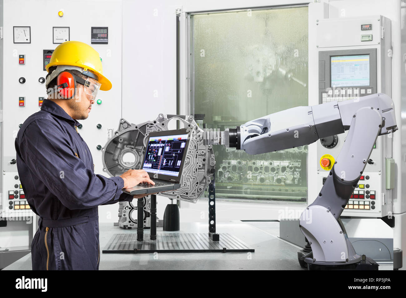 Engineer using laptop computer control automatic robotic hand with CNC machine in automotive ...