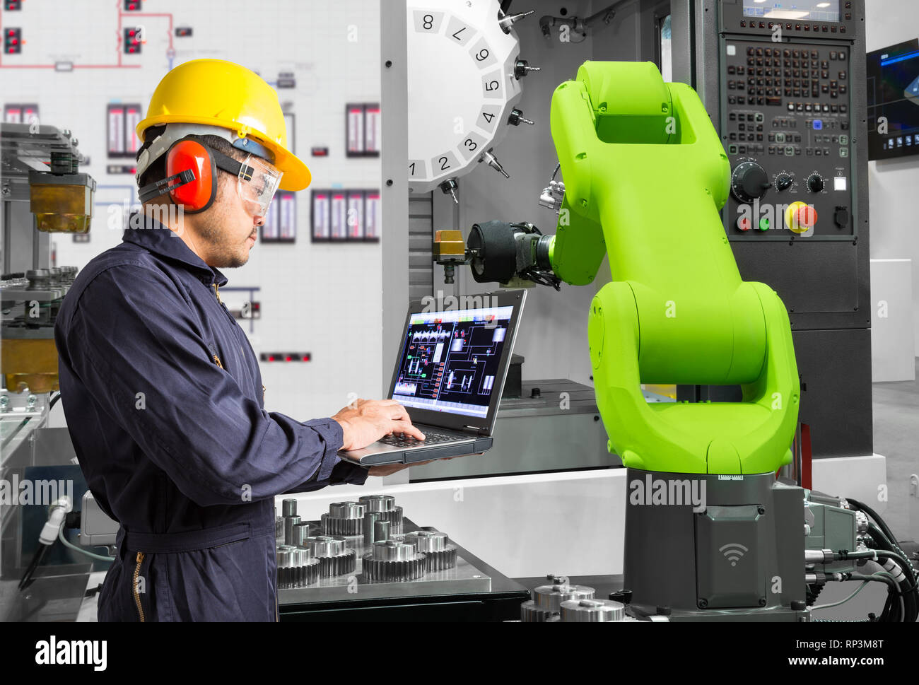 Engineer using laptop computer control automatic robotic hand machine tool with CNC machine in ...