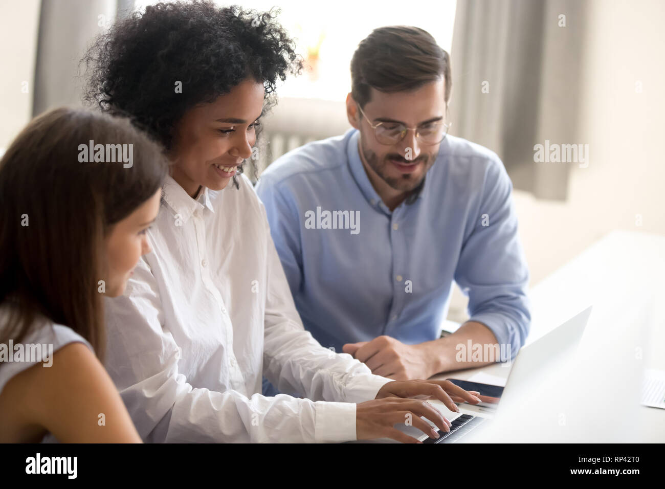 African female team leader typing using computer sitting together with ...
