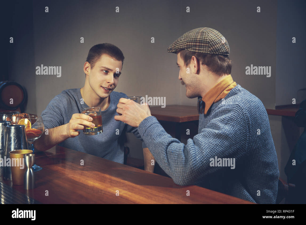 Two young men in casual clothes talking while sitting at bar counter in ...