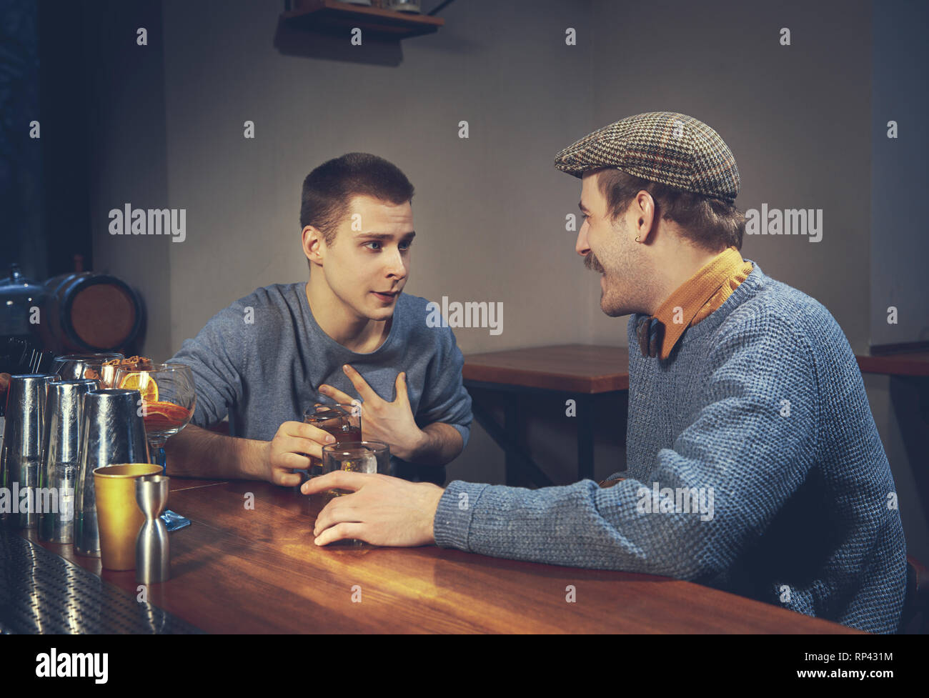 Two young men in casual clothes talking while sitting at bar counter in pub Stock Photo - Alamy