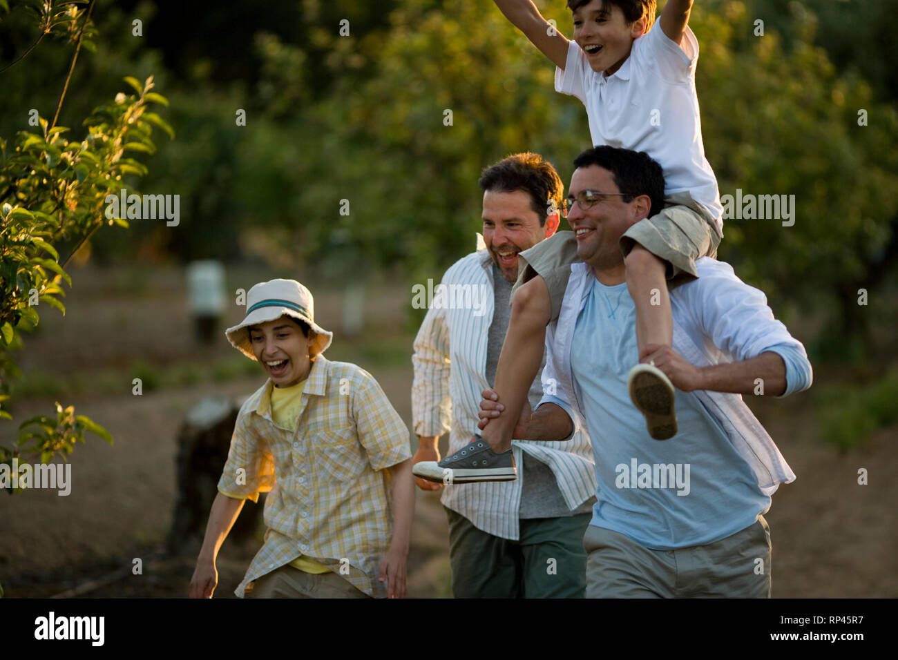 A man giving his son a piggyback ride and running with their friends ...