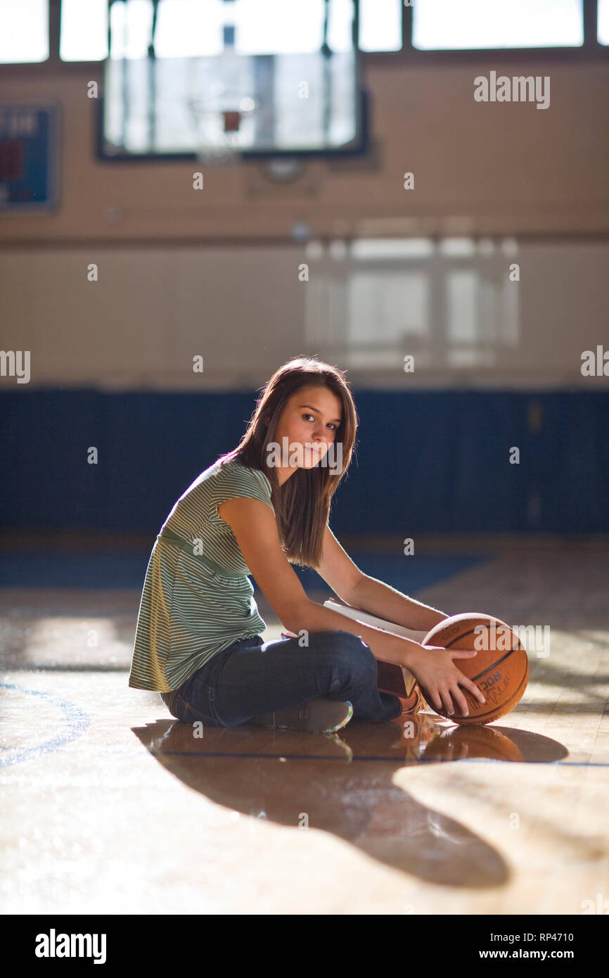 Teenage girl sitting on basketball court holding ball Stock Photo - Alamy