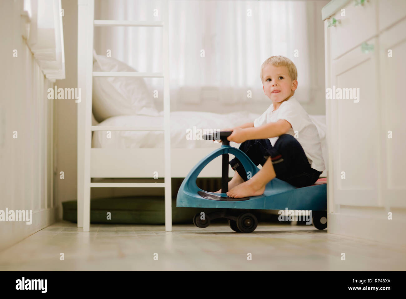 Boy riding on toy car in house Stock Photo - Alamy
