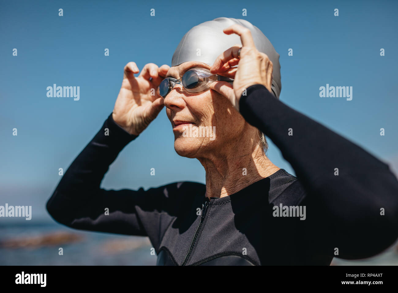 Close up of a senior woman in swim wear standing near the sea. Female ...