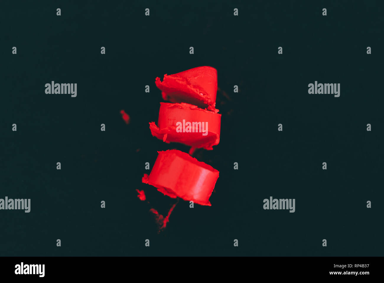 red lipstick cut in chunks on black background, high contrast dark ...