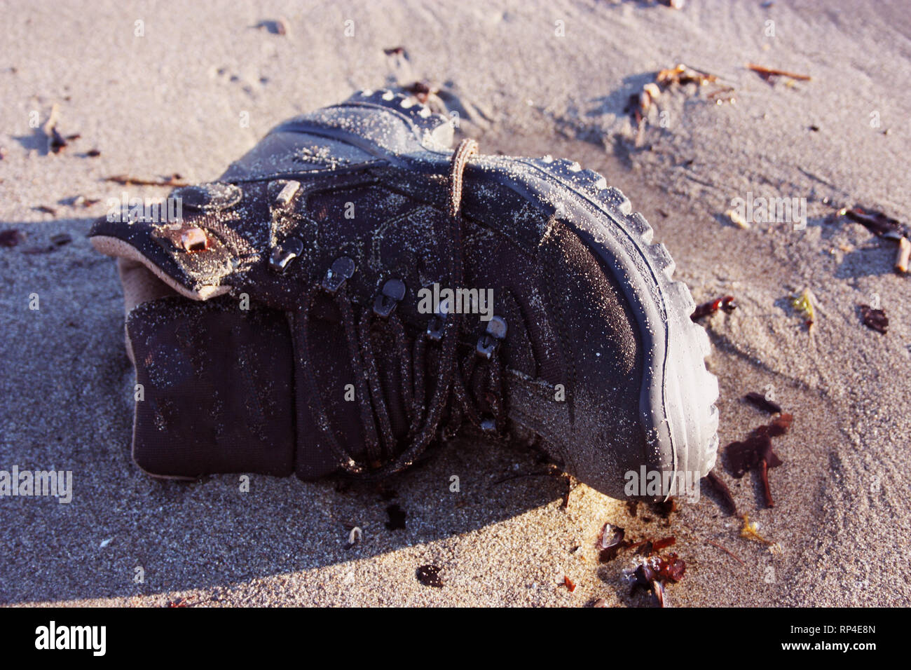 work boot. object of clothing abandoned among the dirt on a sandy beach ...