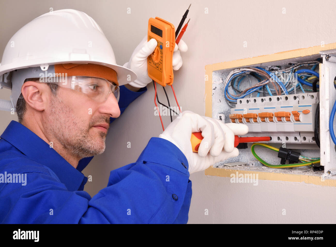 Electrical installer with protective elements working in an electrical ...