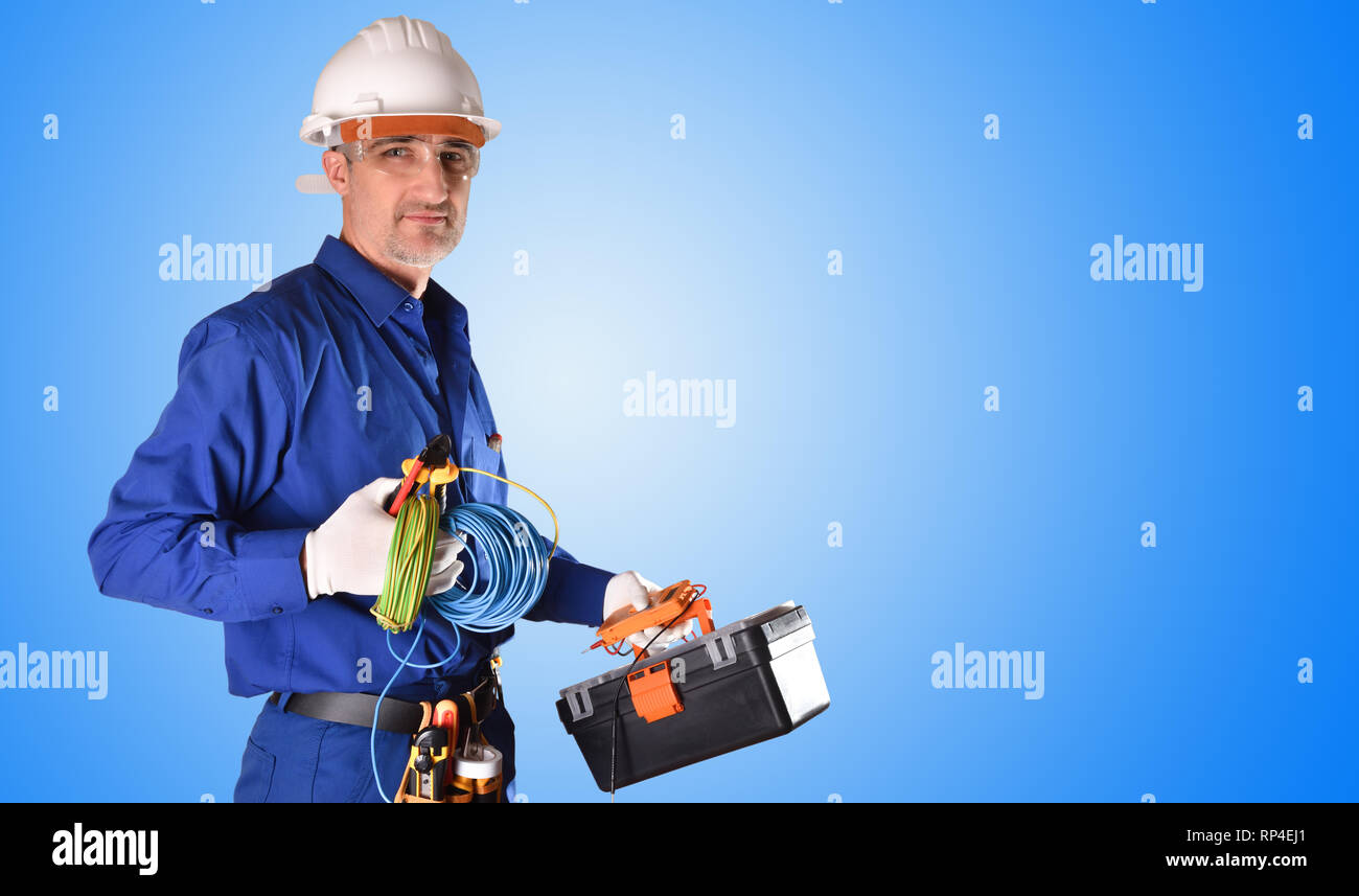 Uniformed electrician in blue overalls and safety protections and tools ...