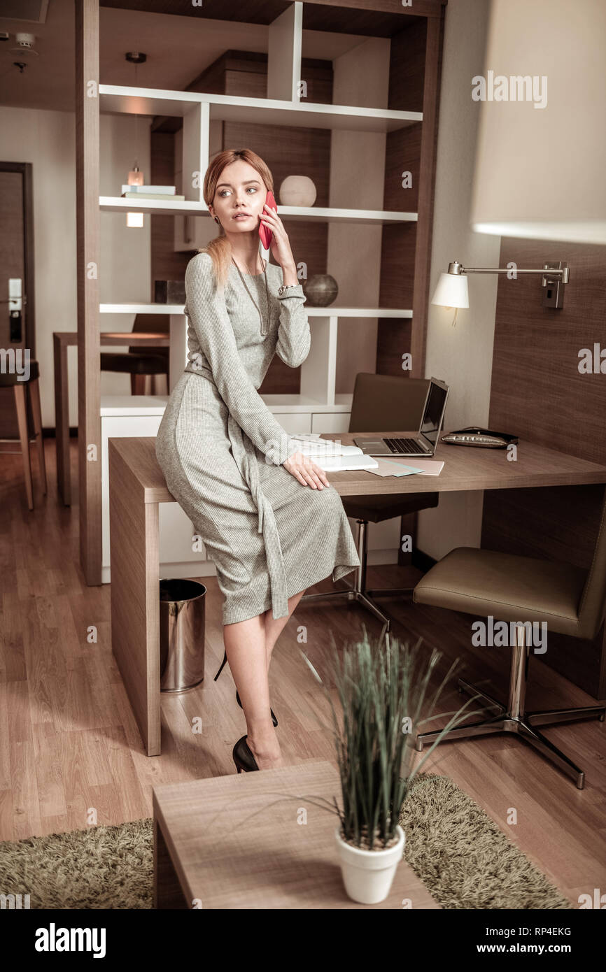 Businesswoman wearing long grey dress calling her colleague Stock Photo ...
