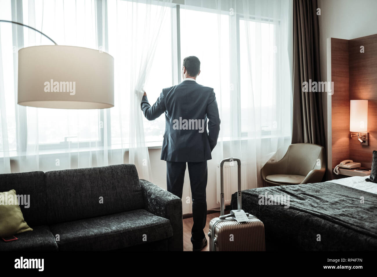 Businessman wearing dark suit looking into window at his hotel Stock ...