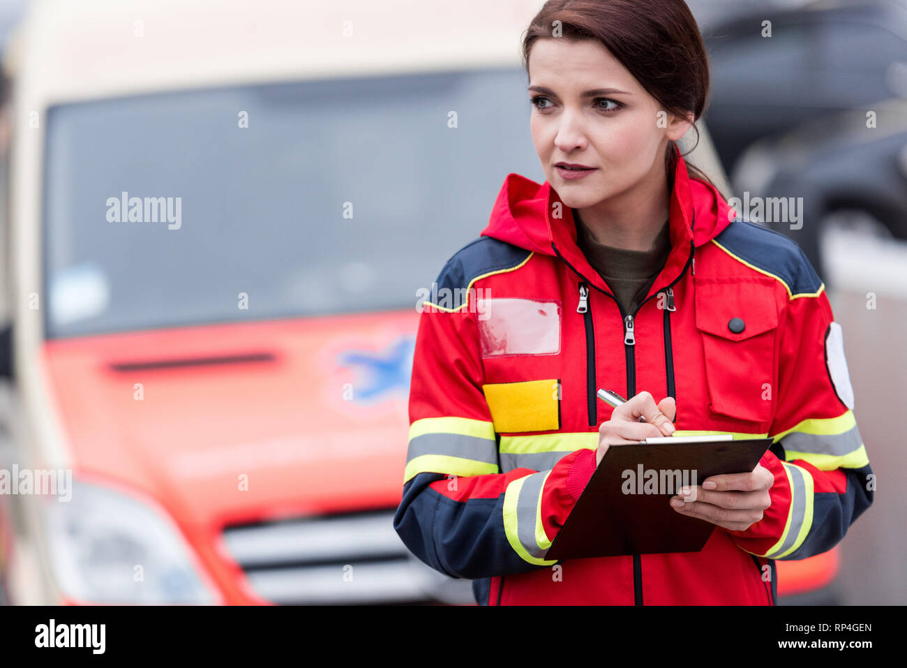 Female paramedic in red uniform writing in clipboard Stock Photo - Alamy