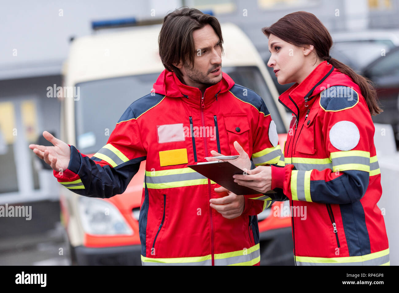 Paramedics in red uniform with clipboard talking on street Stock Photo ...