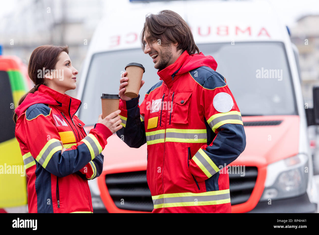 Smiling paramedics drinking coffee in front of ambulance car Stock ...