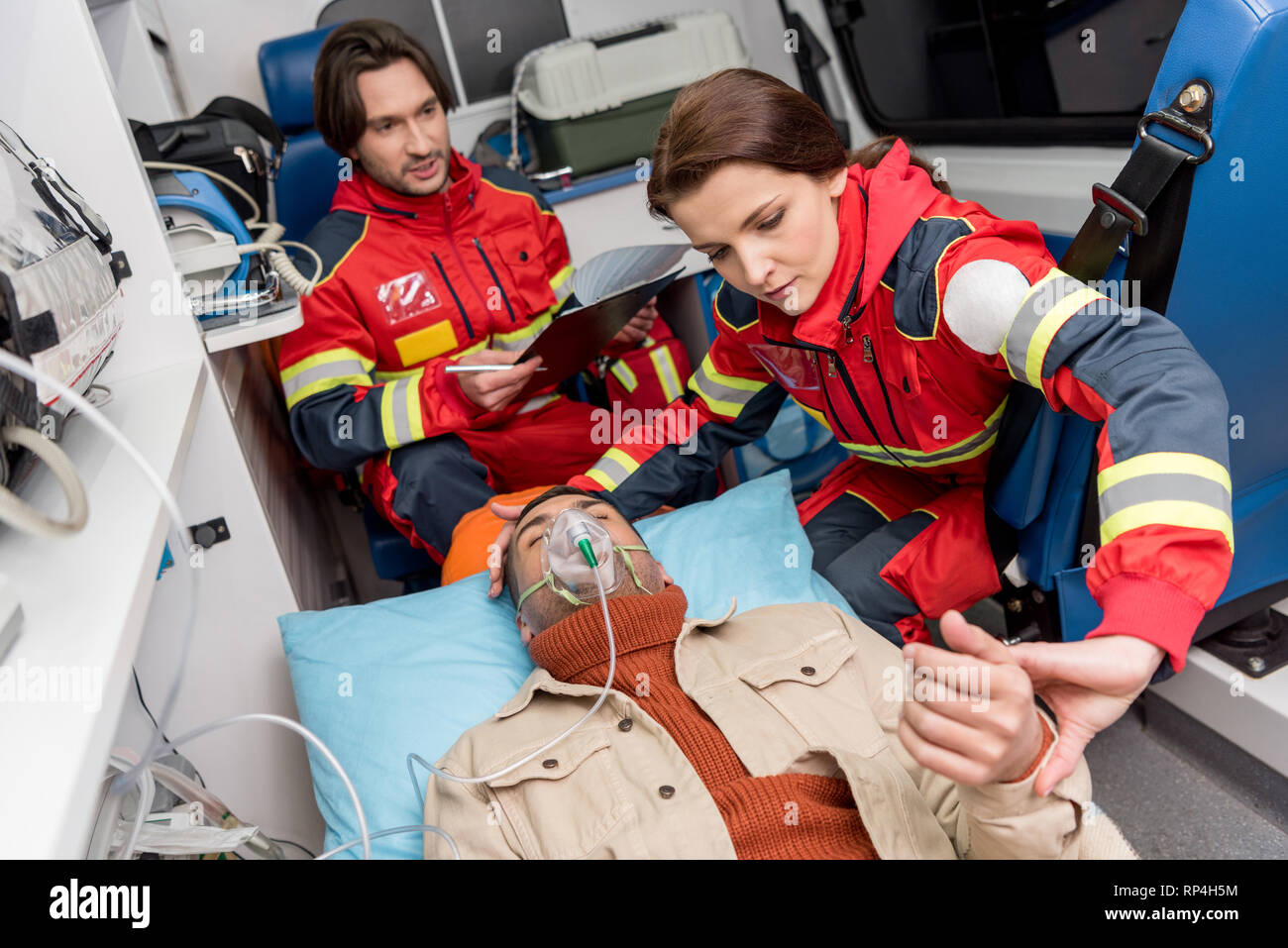 Paramedic holding oxygen mask on patient and checking pulse Stock Photo ...