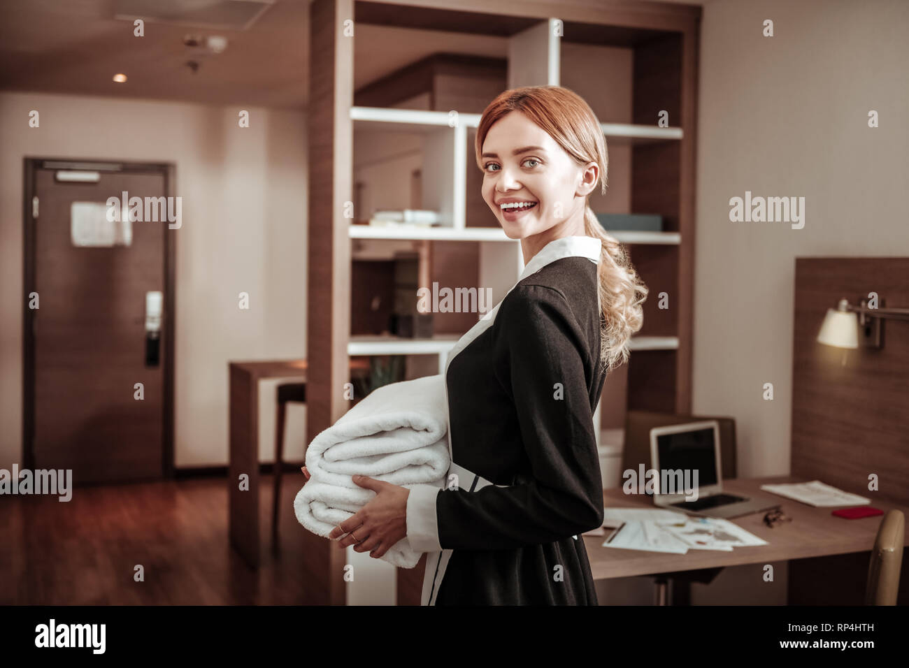 Cheerful maid wearing nice uniform feeling good while working Stock ...